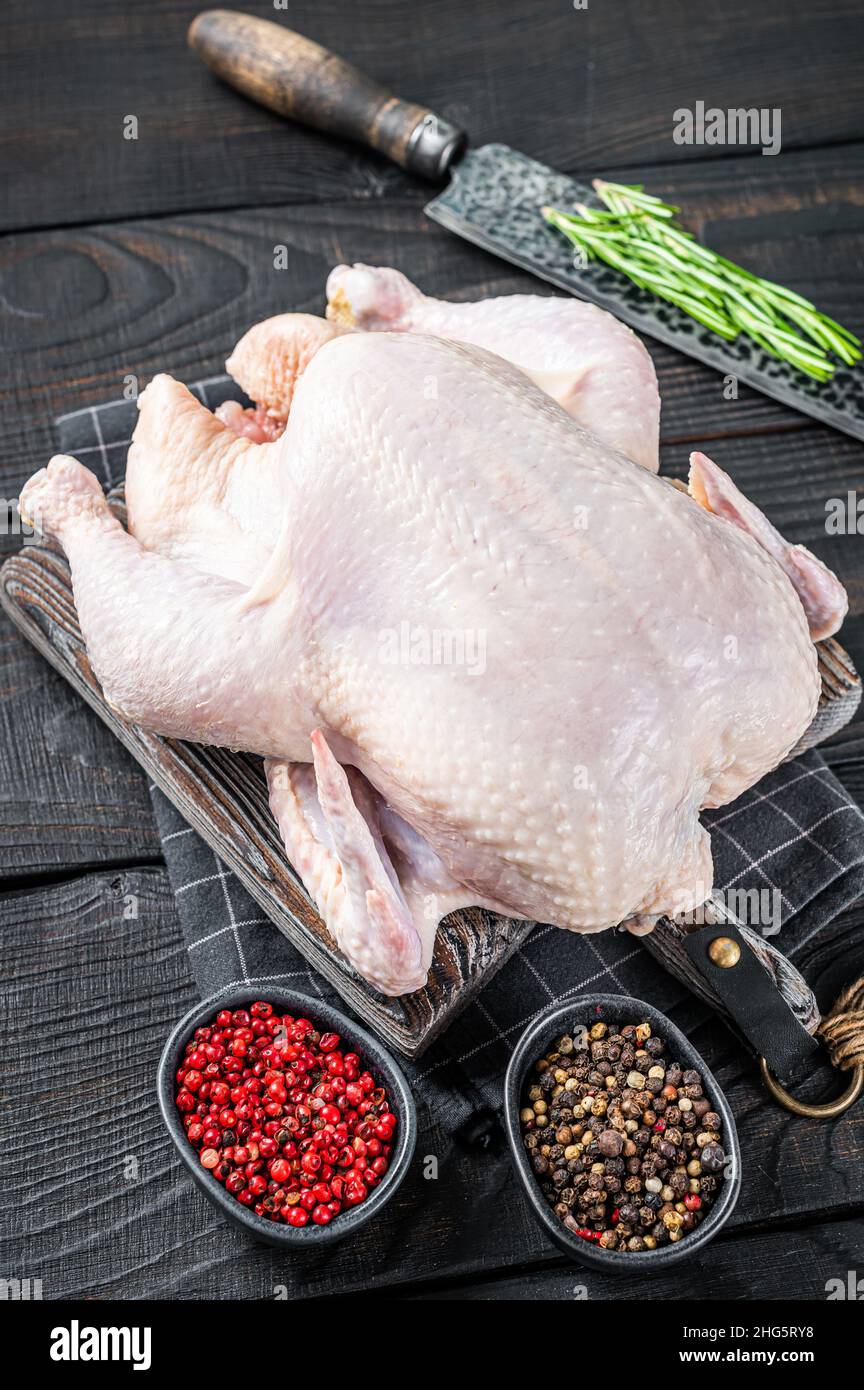 Raw whole chicken, poultry meat on a wooden board with herbs. Black ...