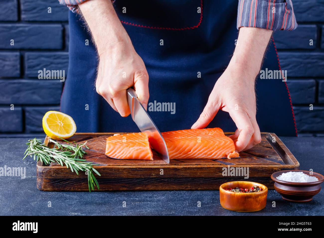 Man is cutting salmon fillet. Chef cutting a fish fillet on a rustic ...