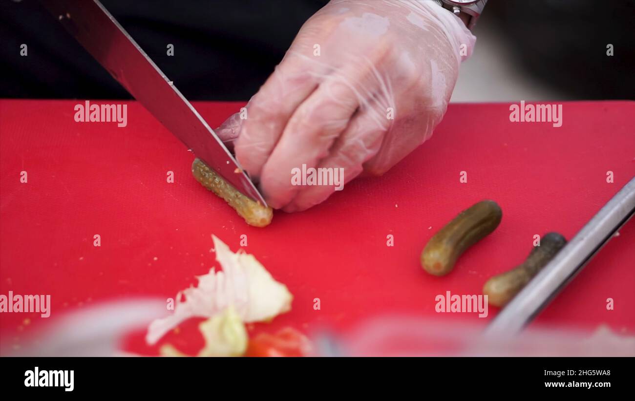 knife cutting pickles on wooden board. cook cuts pickled cucumbers ...