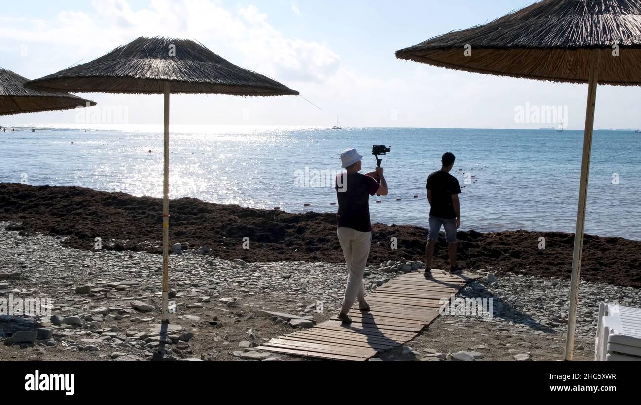 Videographer taking pictures and video of the ocean views and a man ...