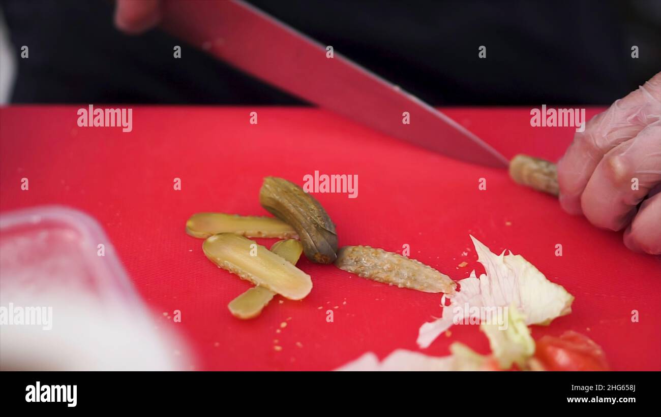 knife cutting pickles on wooden board. cook cuts pickled cucumbers ...
