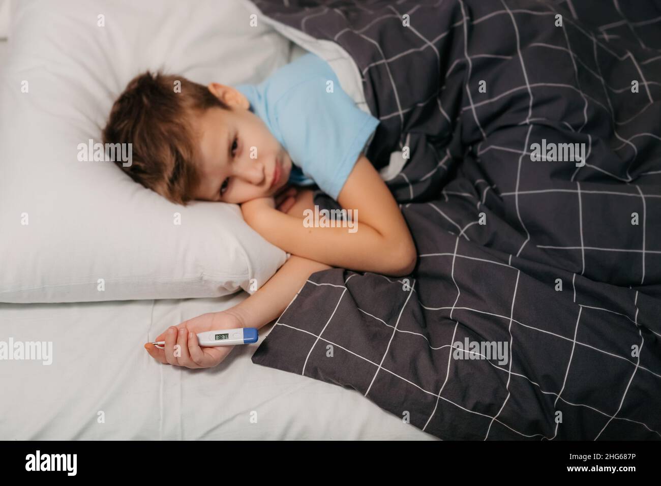 Sick child laying in bed and holding termometer Stock Photo - Alamy