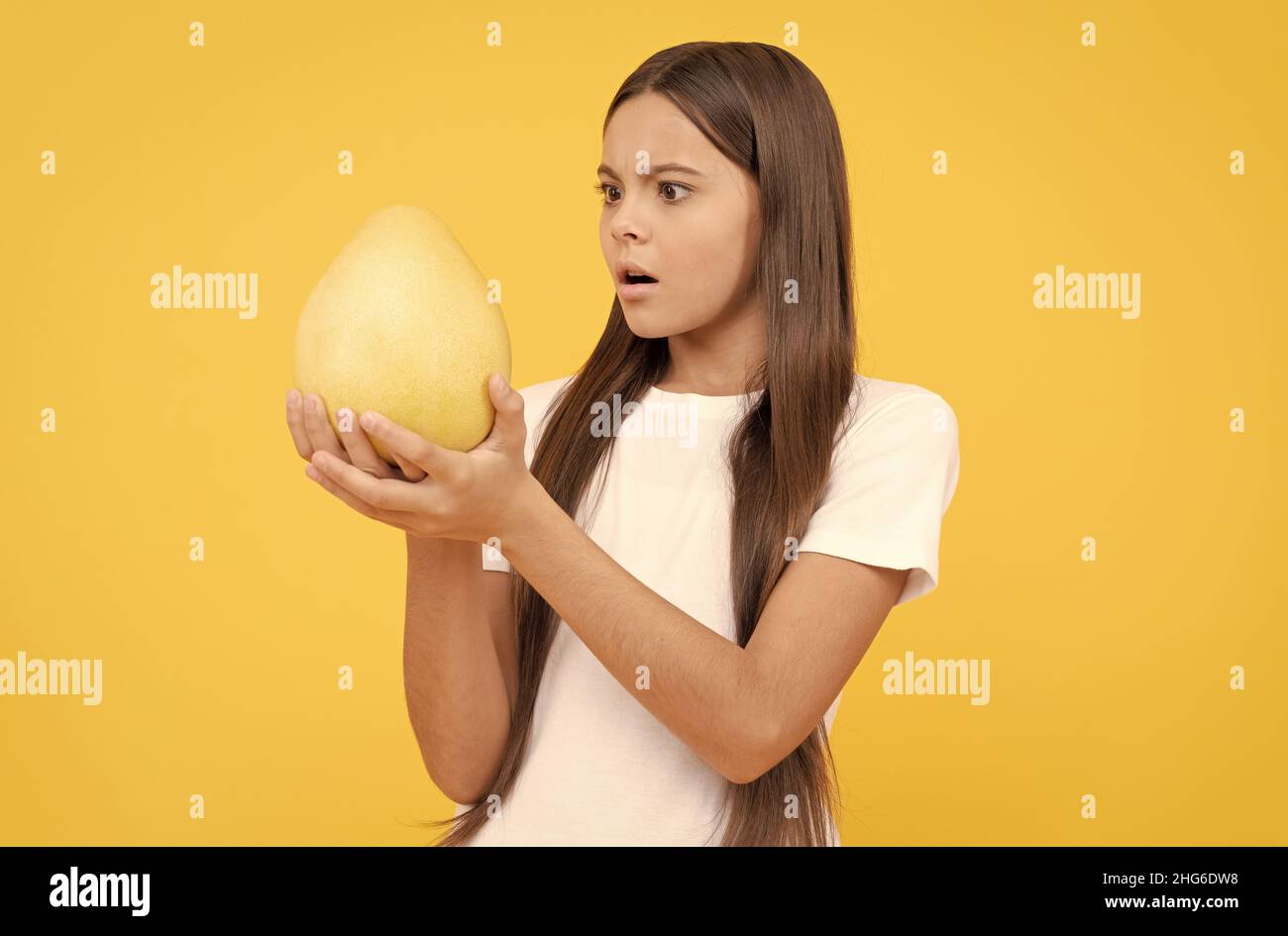 serious teen girl hold big citrus fruit of yellow pomelo full of ...