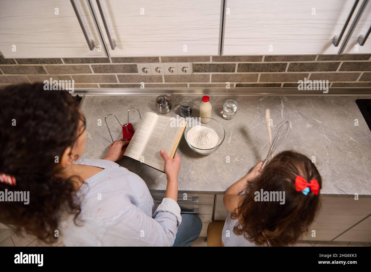 Overhead view of mother and daughter cooking food together while ...