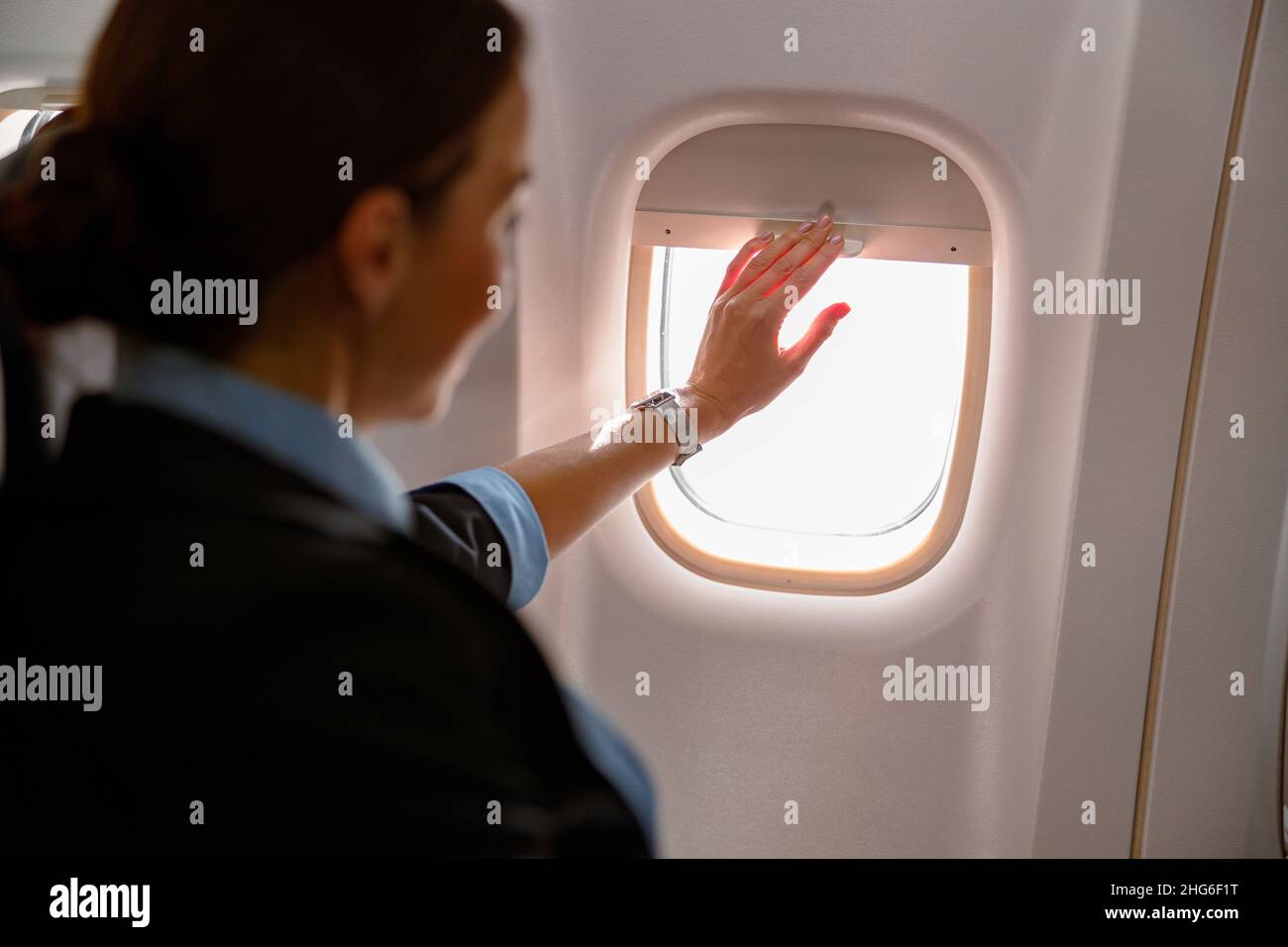 Female flight attendant closing window in aircraft Stock Photo - Alamy