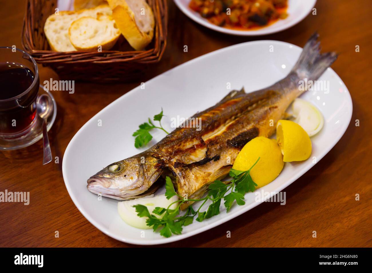 Delicious fish dish, fried bass served with onion, lemon and parsley ...