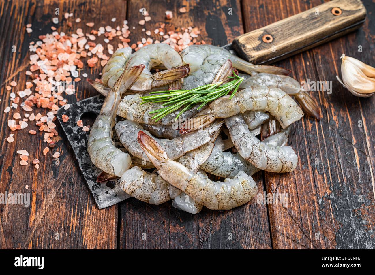 Raw Headless tiger shrimps prawns on a butcher cleaver. Dark wooden ...