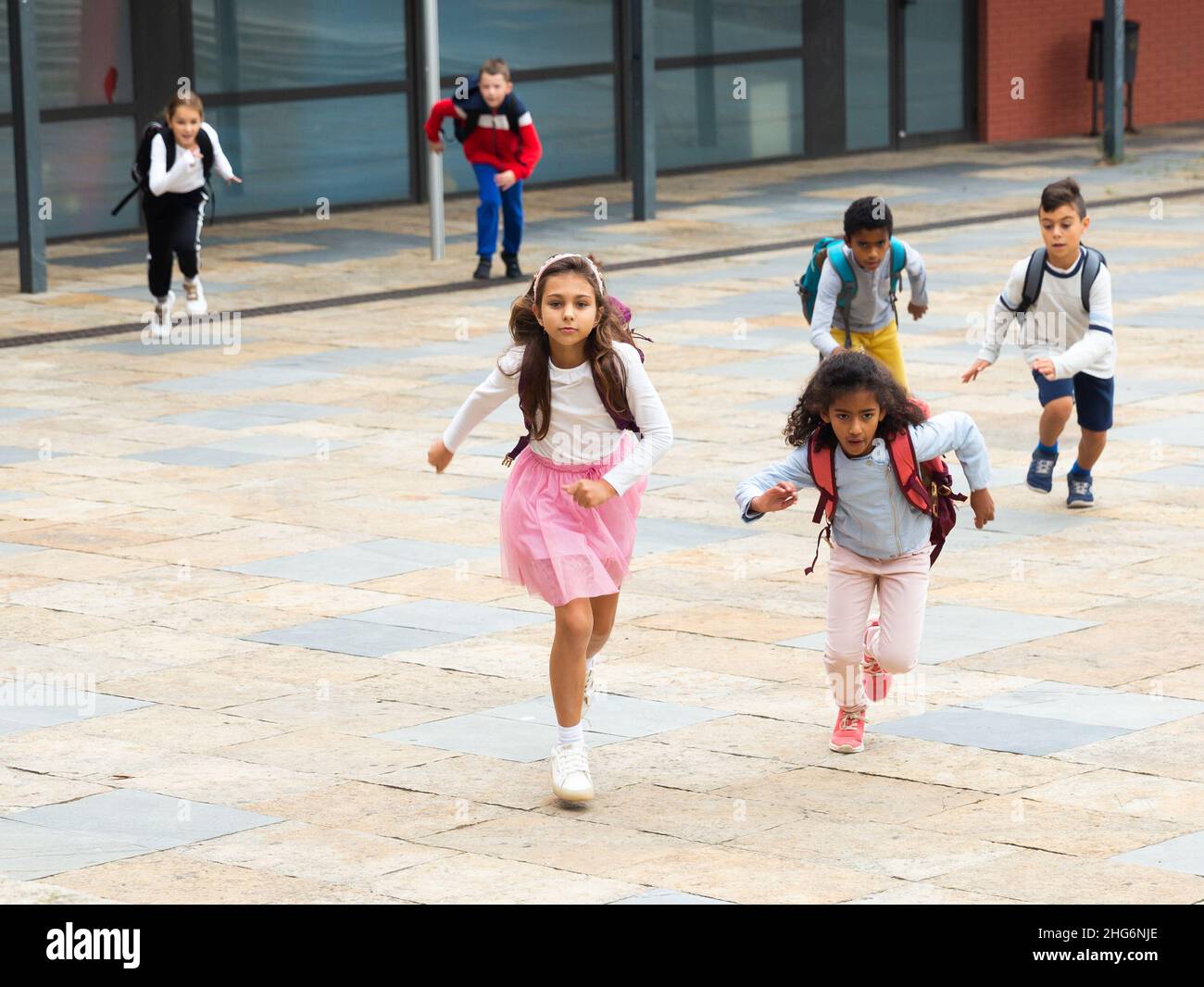 Tween boys and girls with school backpacks running in schoolyard Stock ...