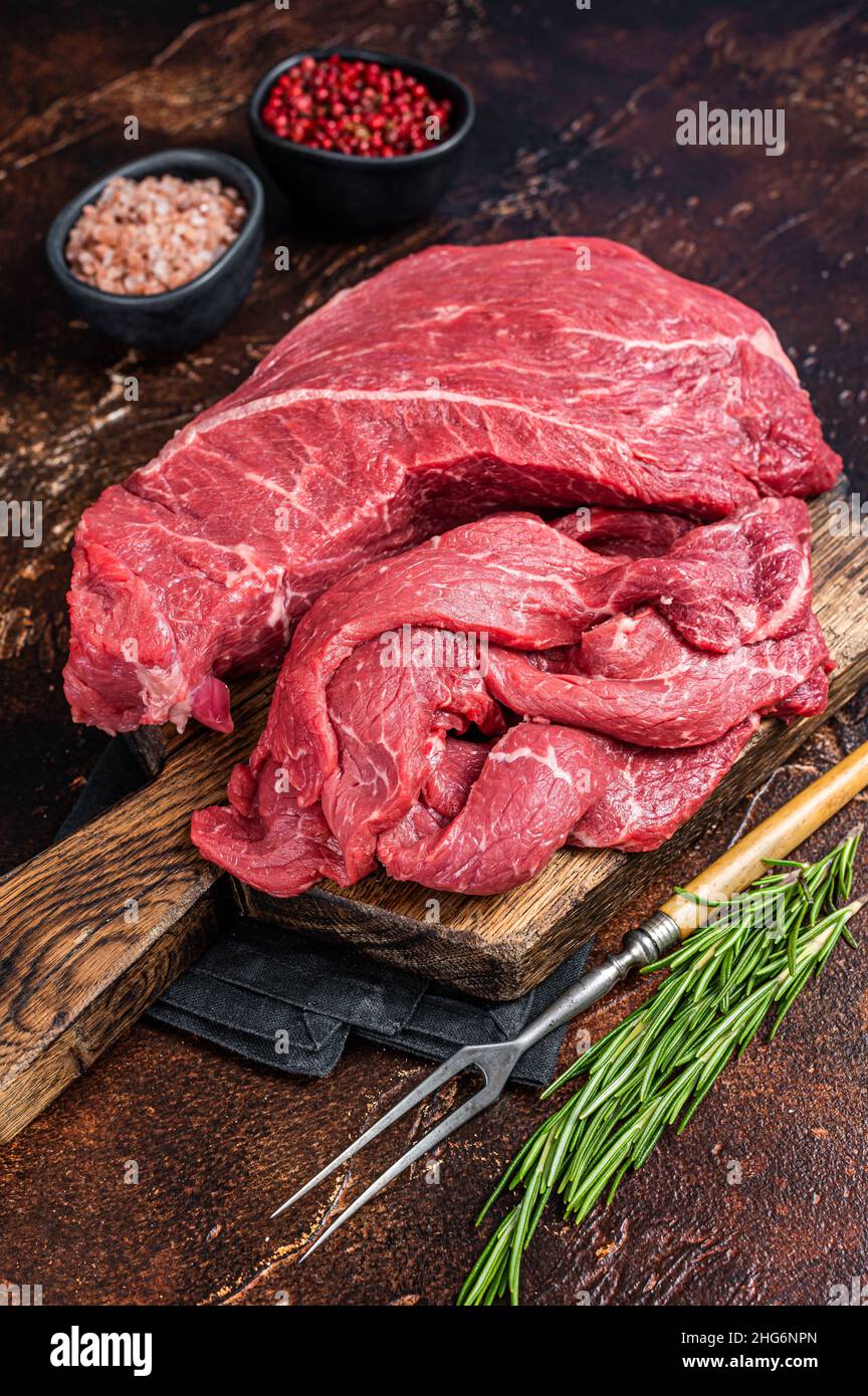 Raw Beef meat fillet Sliced on wooden cutting board. Dark background ...