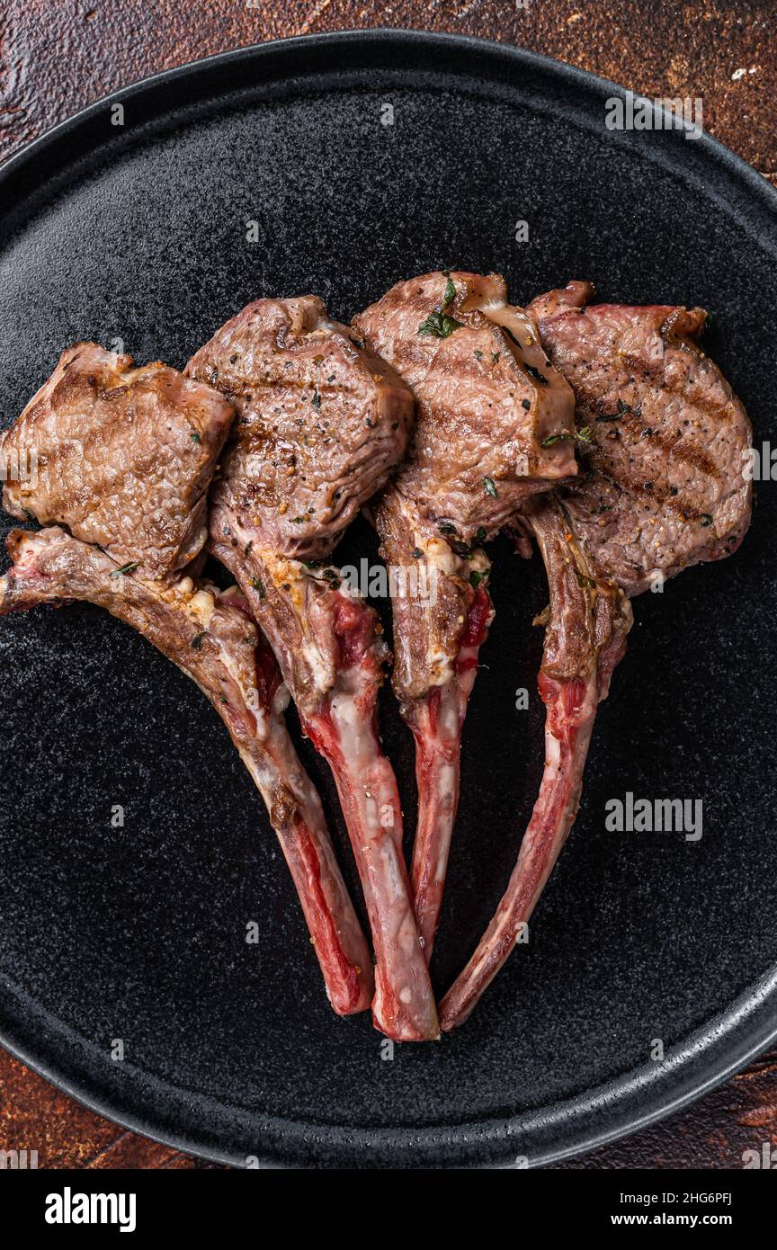 BBQ Grilled lamb chops steaks in a plate. Dark background. Top view ...