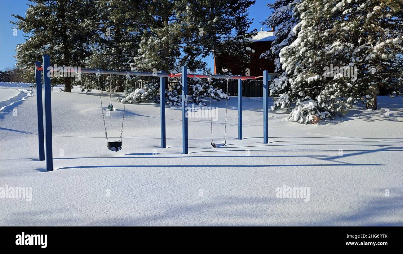 Snowy swings on the playground in a public park Stock Photo - Alamy