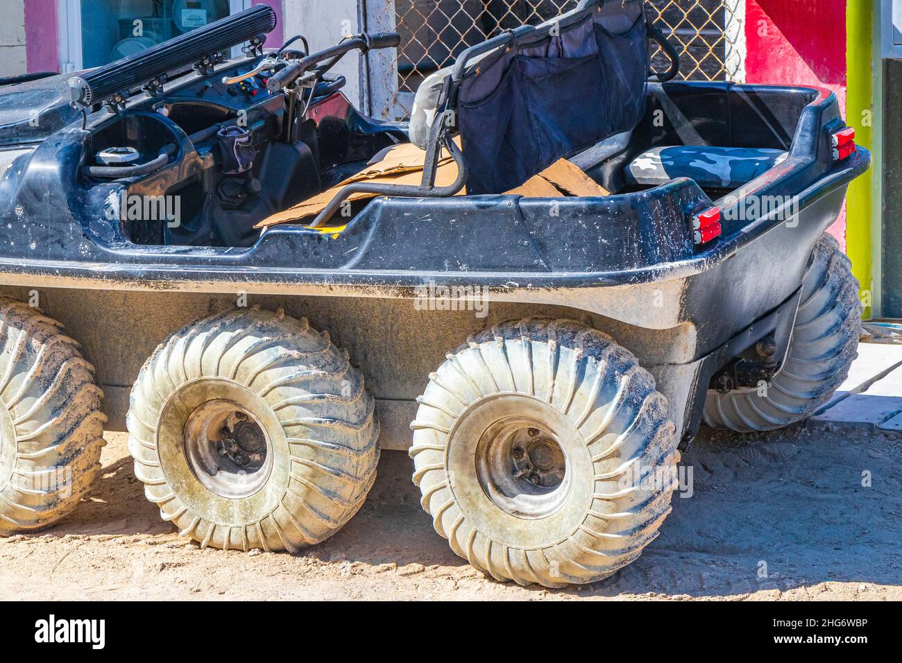 Buggy car golf cart with 6 wheels on muddy street in the village on ...