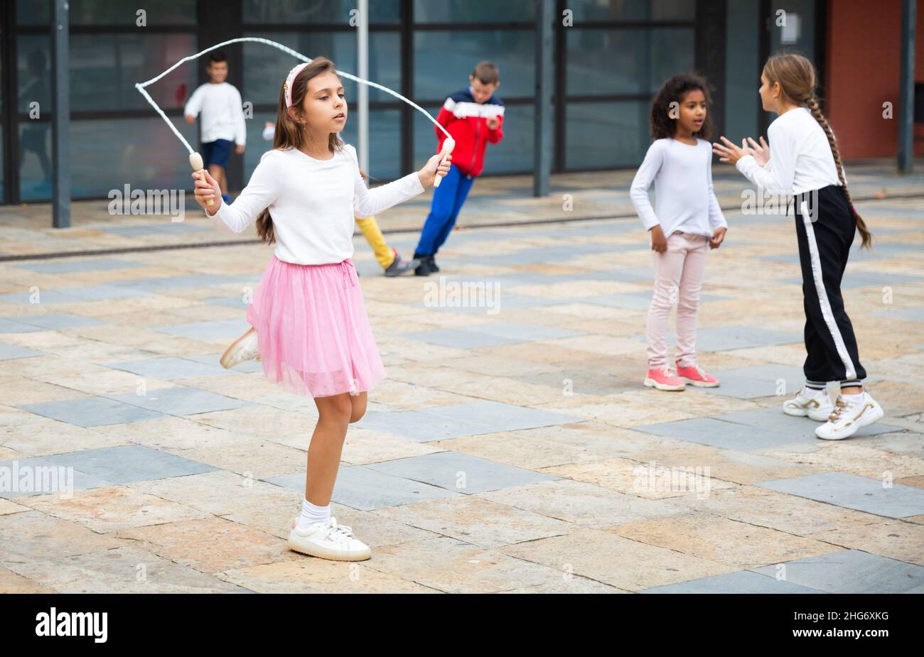 Tween girl in pink skirt jumping rope in schoolyard during recess Stock ...