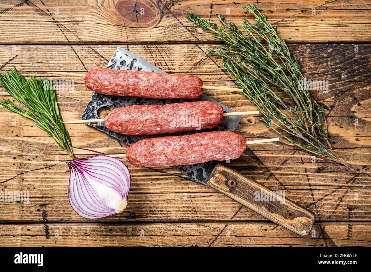 Fresh Raw kofta or lula kebabs skewers on a butcher cleaver with herbs ...