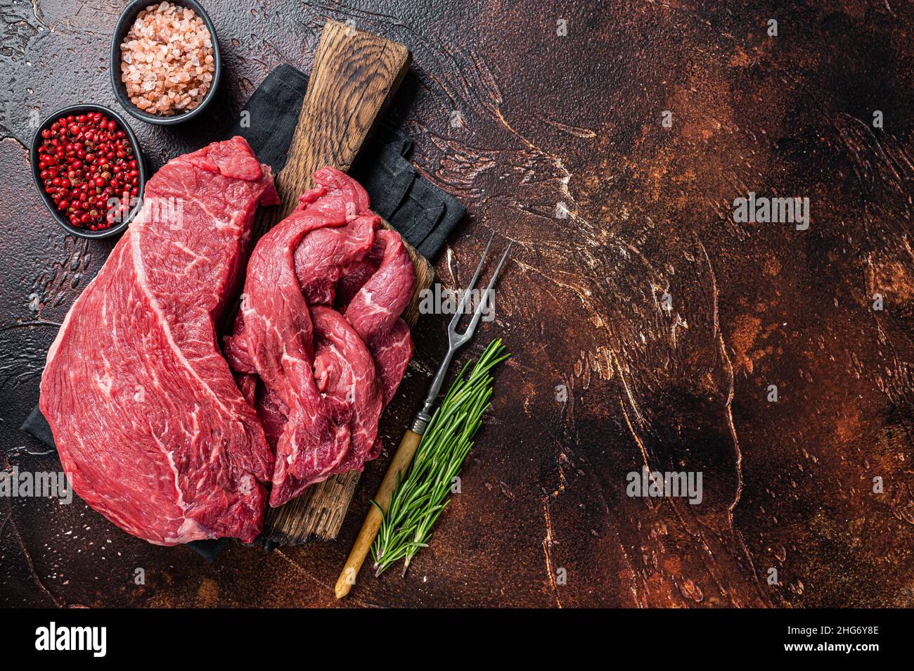 Raw Beef meat fillet Sliced on wooden cutting board. Dark background ...