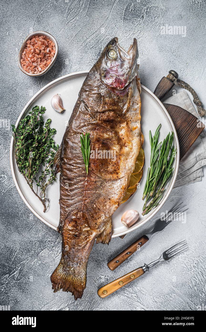 Baked silver trout, roasted fish on a plate with herbs. White ...