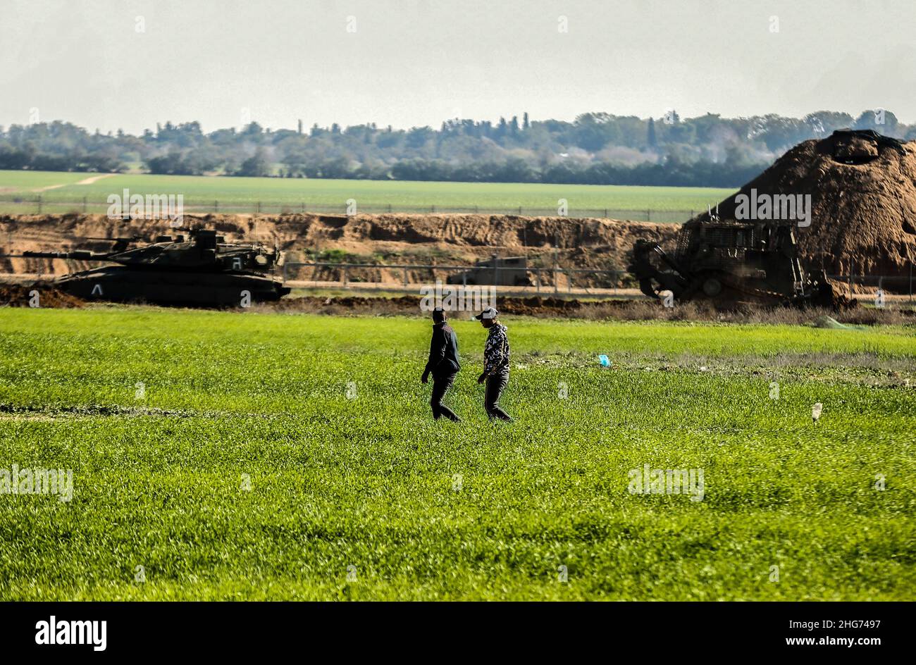Farmers work on a farm near the fence separating Gaza and Israel, while ...