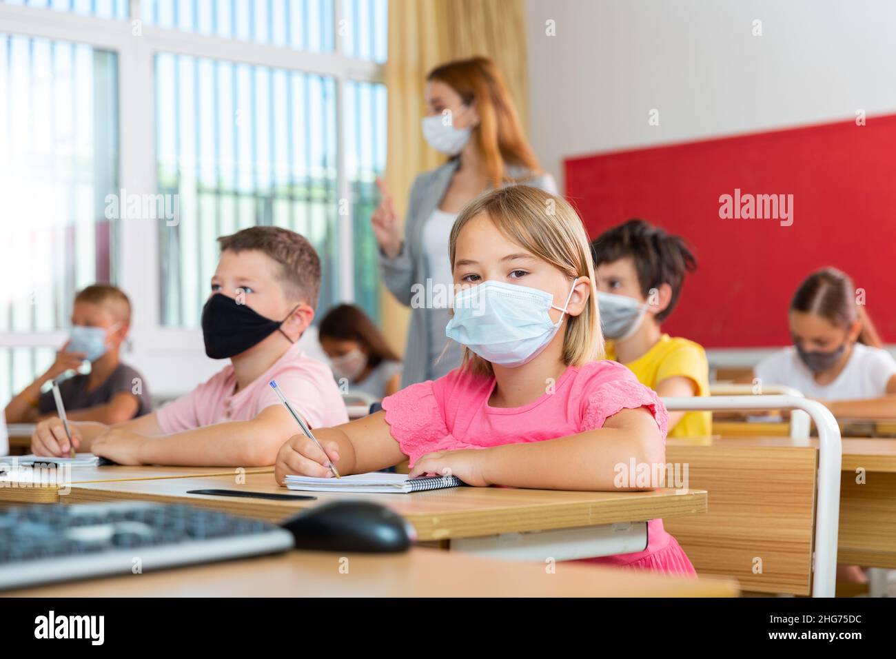 Kids in masks studying in classroom Stock Photo - Alamy