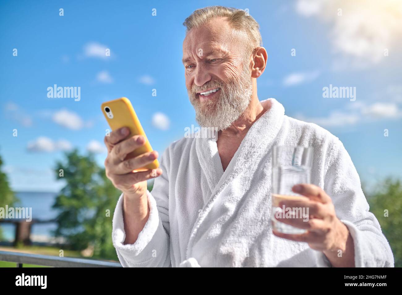 Smiling man reading a text message on his smartphone Stock Photo - Alamy