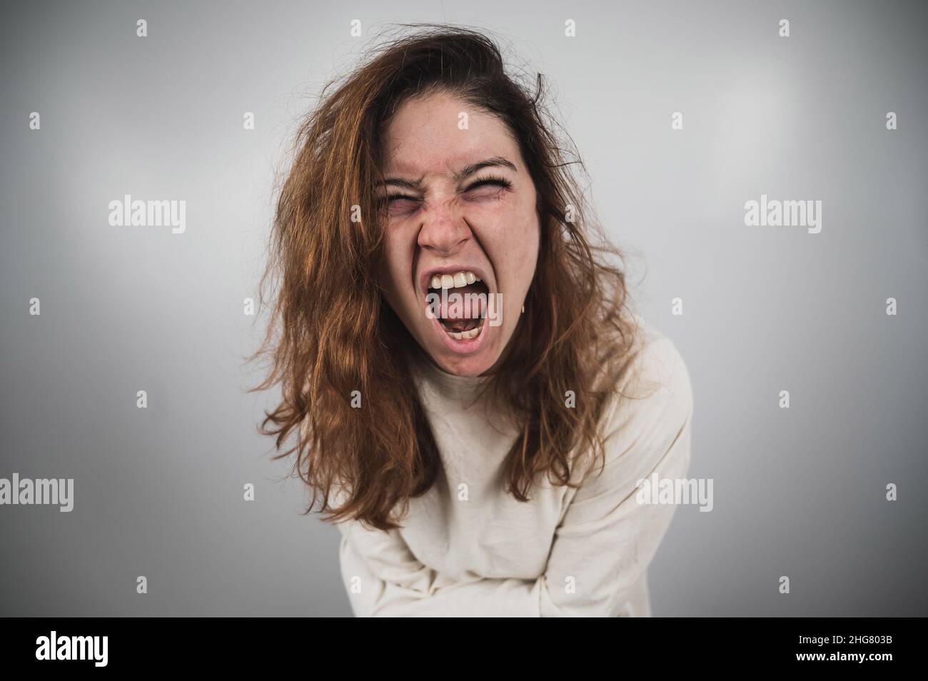 Close-up portrait of insane woman in straitjacket on white background ...