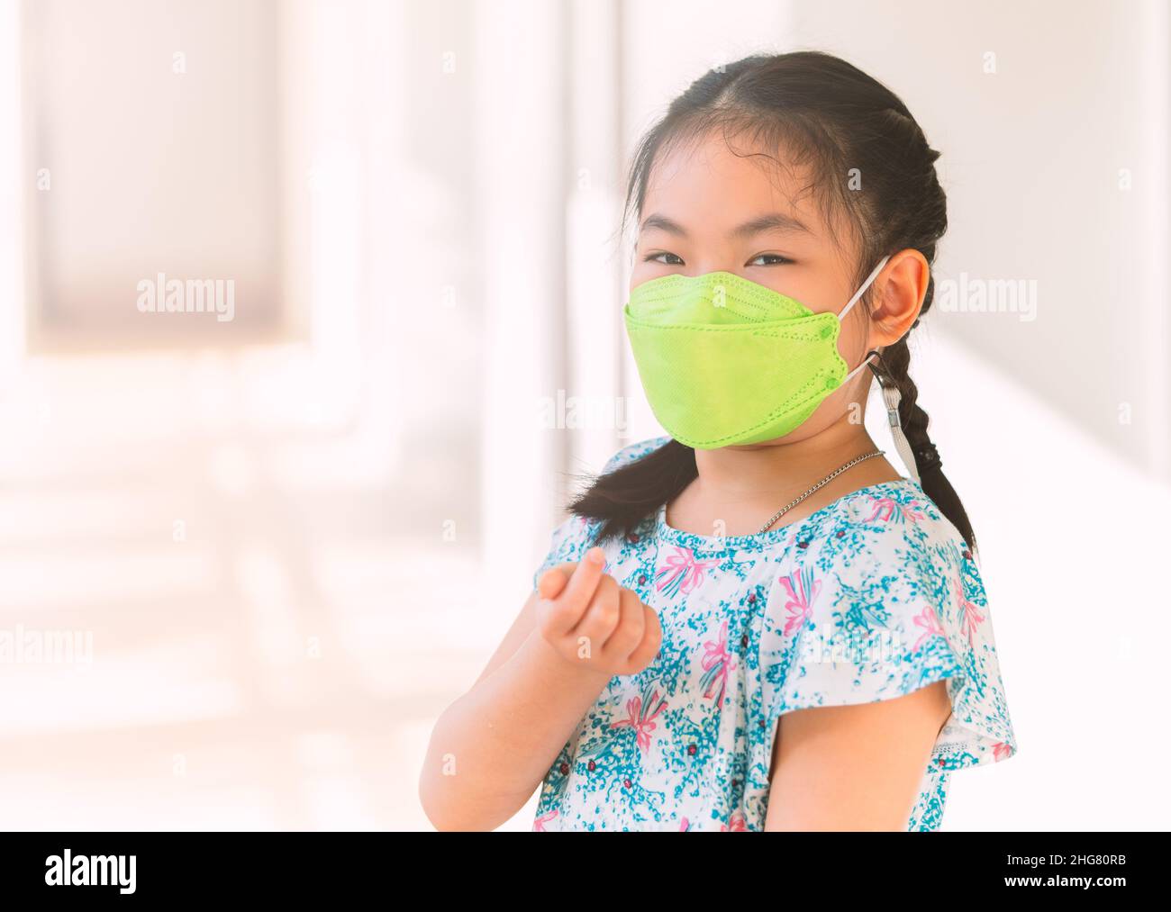 Portrait of Asian little girl wearing green - color face mask ...