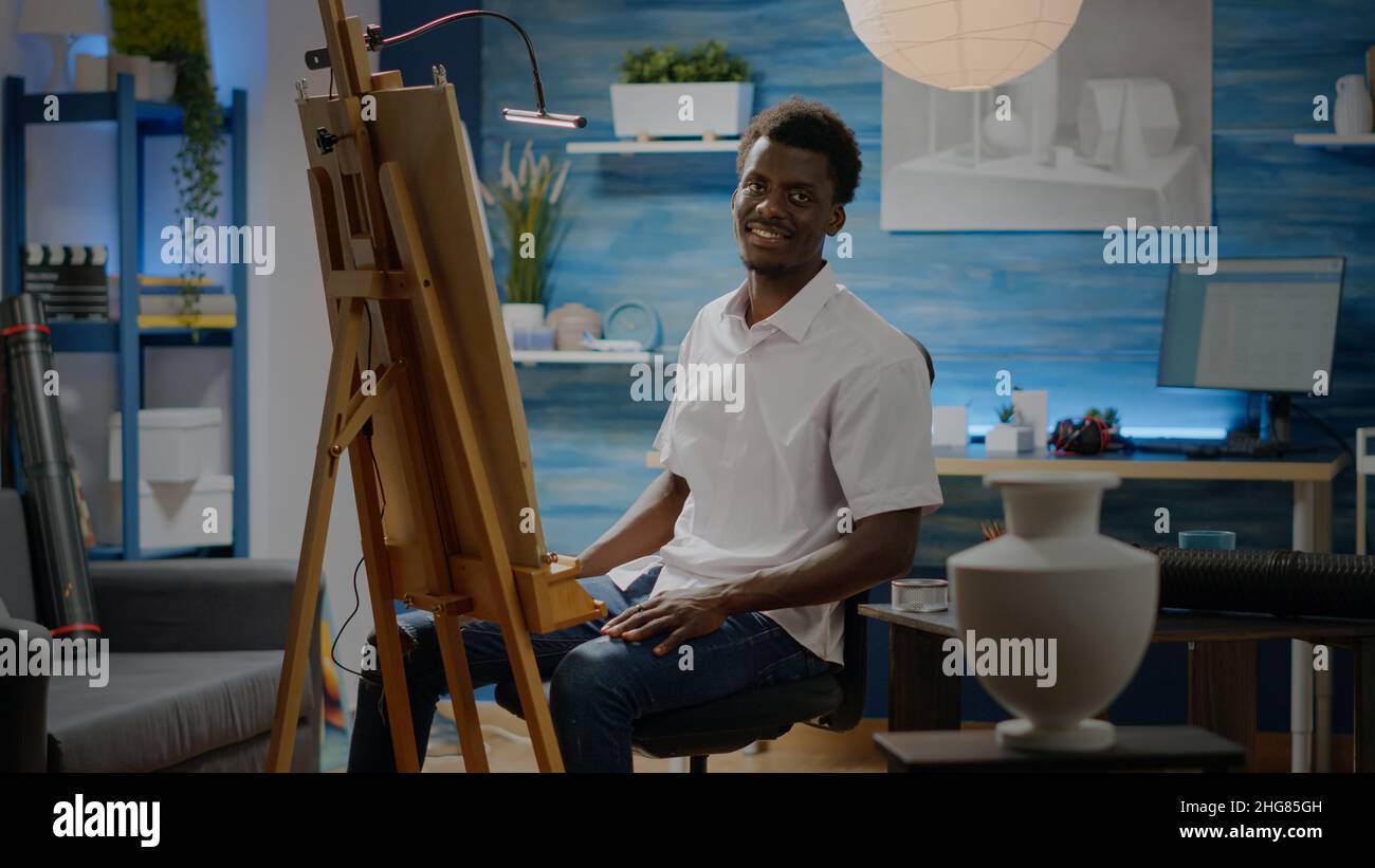 African american person sitting in art studio with drawings and easel ...