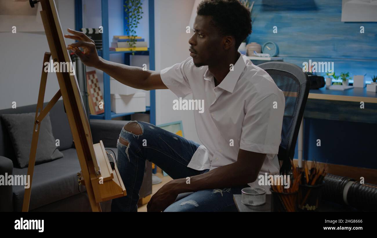 African american man studying vase design with pencil in professional ...