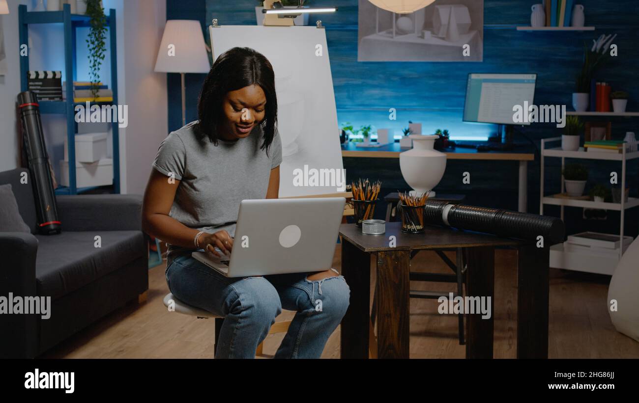 Young artist of african american ethnicity using laptop computer ...
