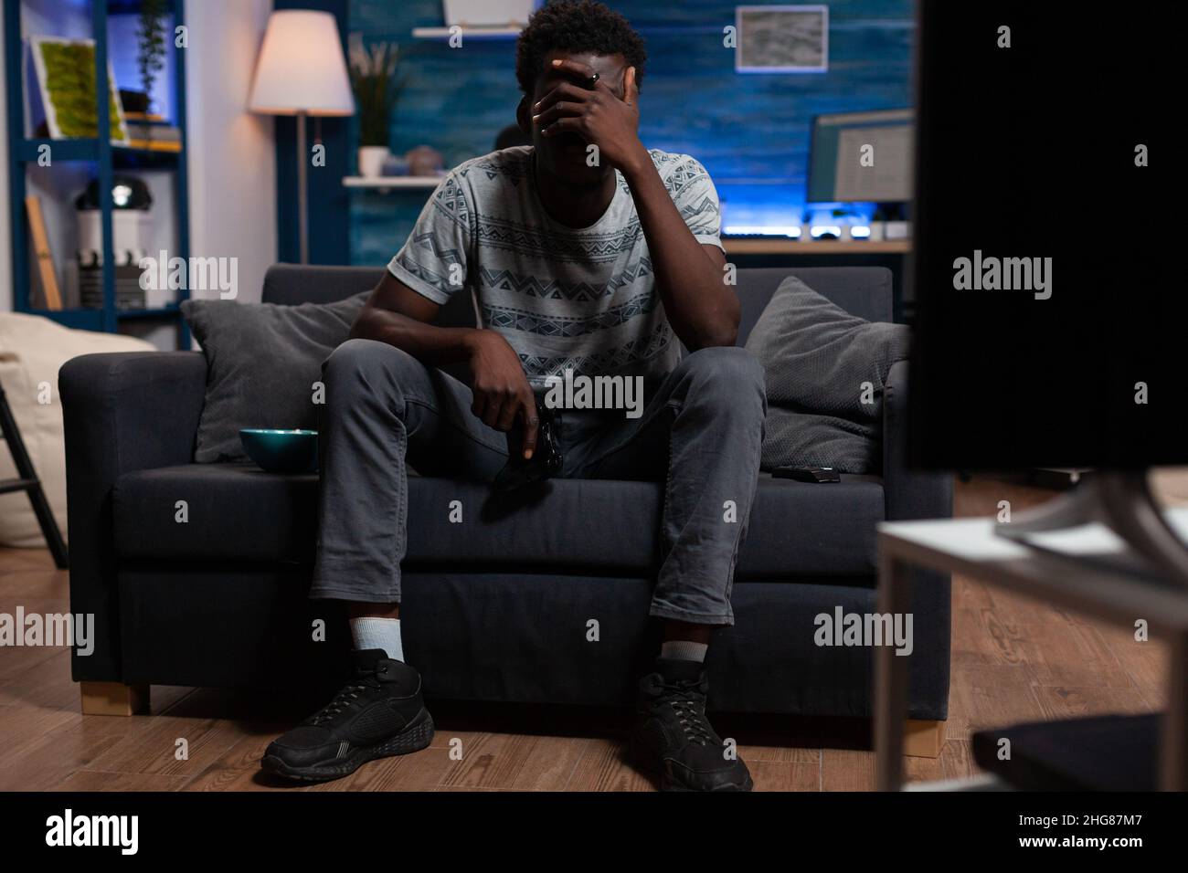 Sad upset cyber player playing video games on television using gaming ...