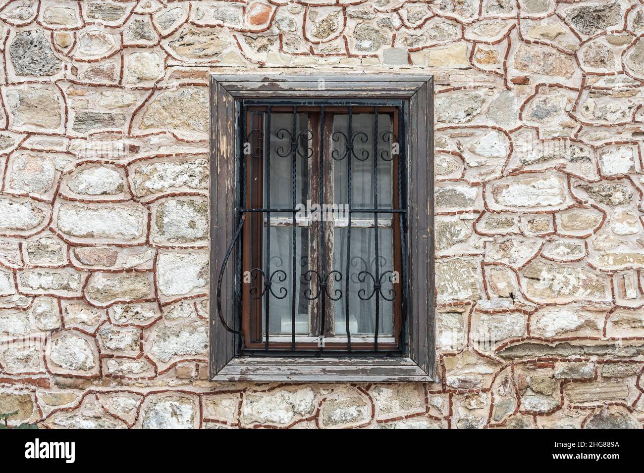 Close-up brown wooden vintage window behind bars in an old stone house ...