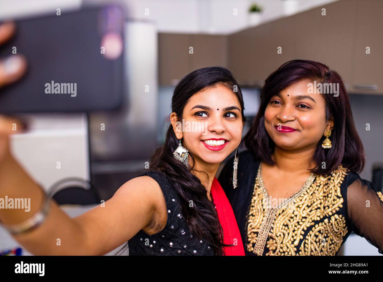 two indian women in saree talk with family by phone video chatting at ...