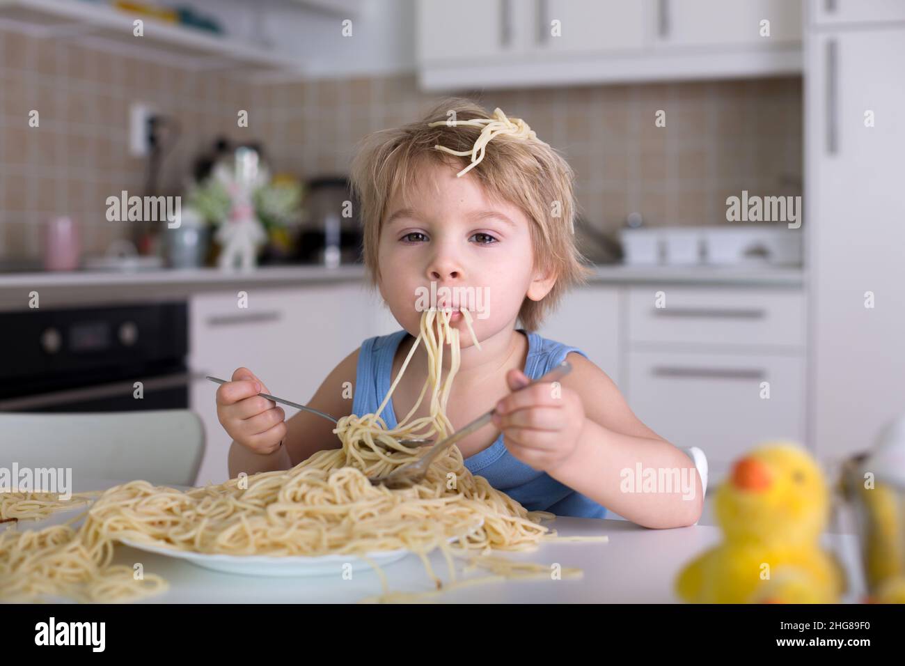 Little blond boy, toddler child, eating spaghetti for lunch and making ...