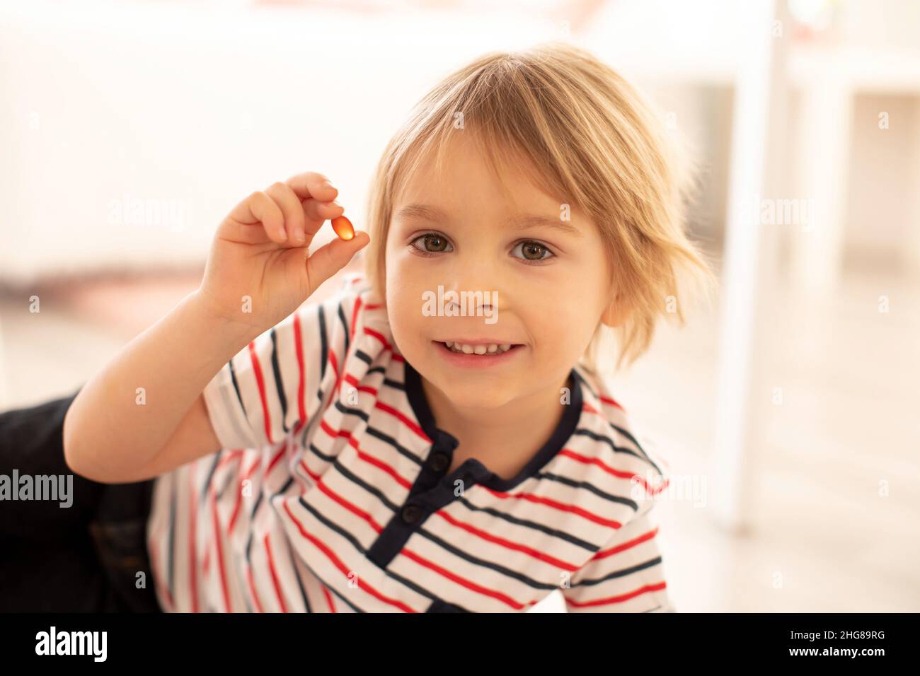 Cute little child, toddler boy, eating alfa omega 3 child suplement ...