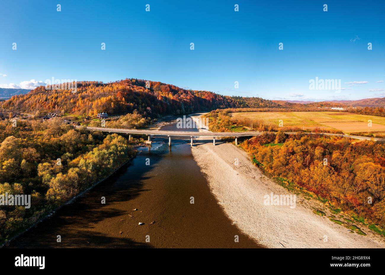 Bridge with asphalt road over narrow shallow river leading to ...