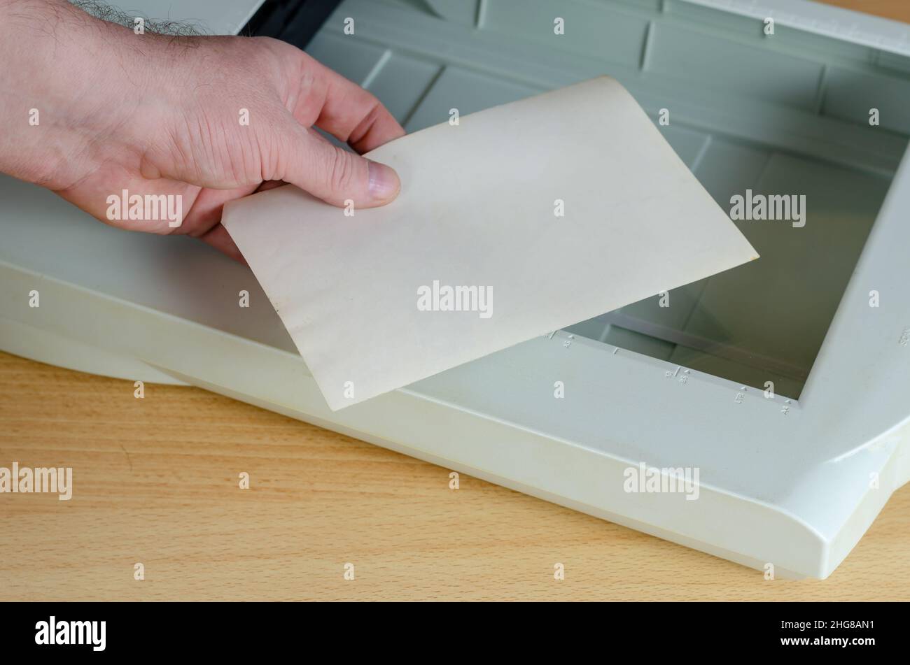 Digitization of a family photo album. A hand places a paper photo on ...