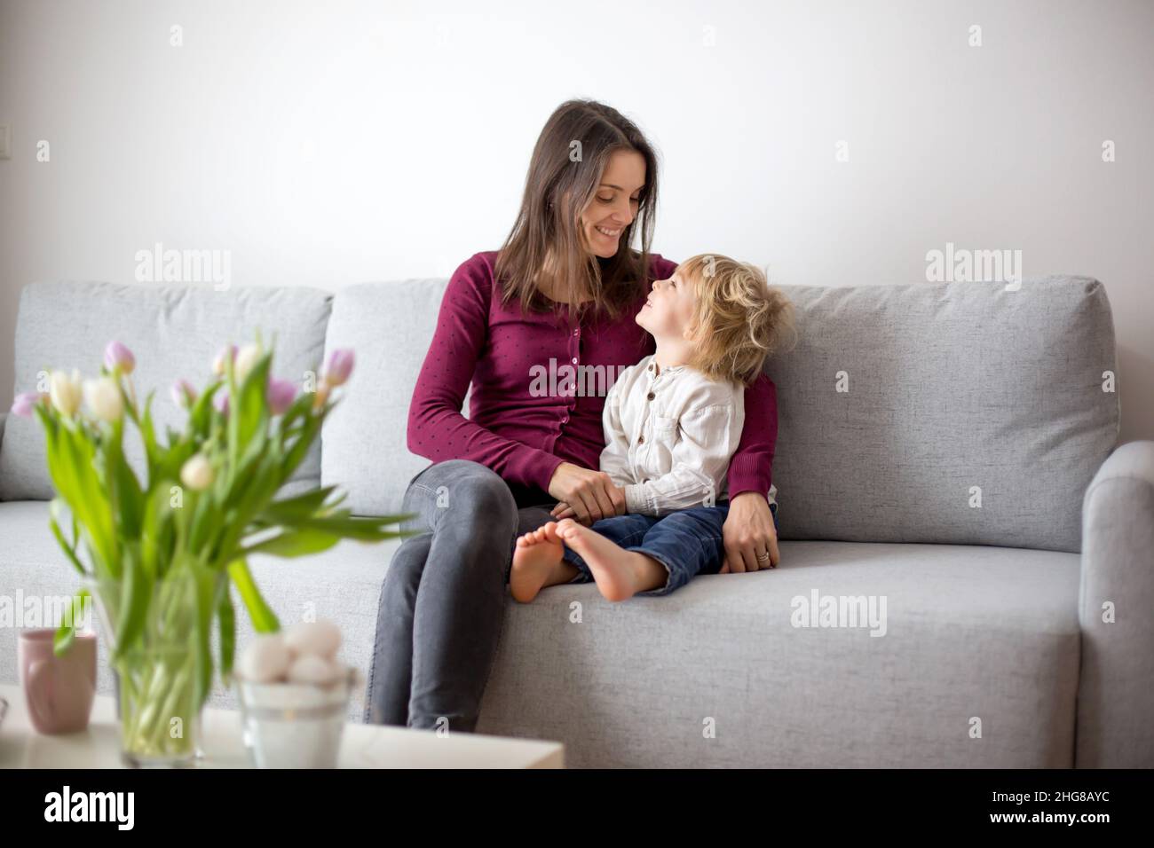 Beautiful blond boy, giving mother flowers and box with little gift for ...