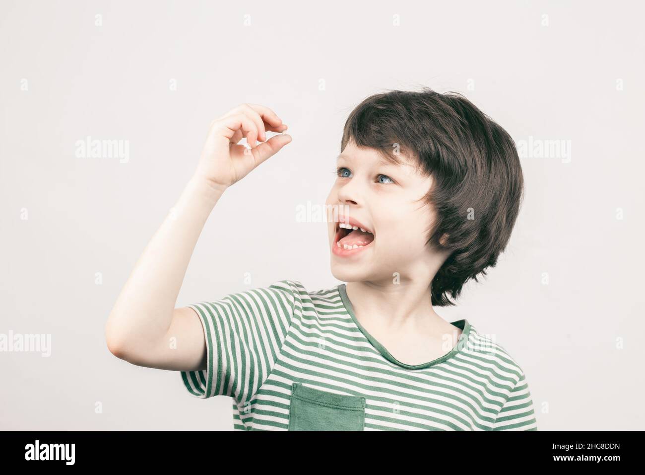 Young toothless boy looking at his first lost bottom front milk tooth ...