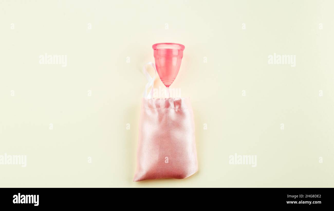 Pink Silicone Menstrual Cup and pink Storage Cloth Bag over beige ...