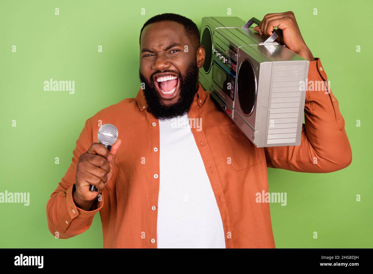 Photo of funny young brunet guy sing hold boom box wear orange shirt ...