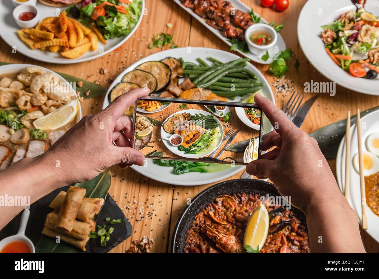 A man takes a photo of food on his smartphone at a Filipino restaurant ...