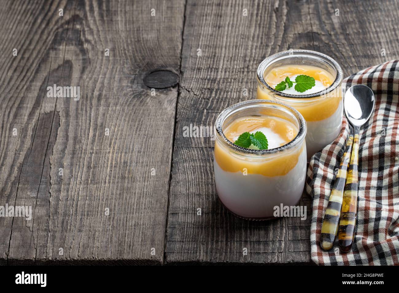 White creamy yogurt with yellow fruitty puree in small jar on wooden ...