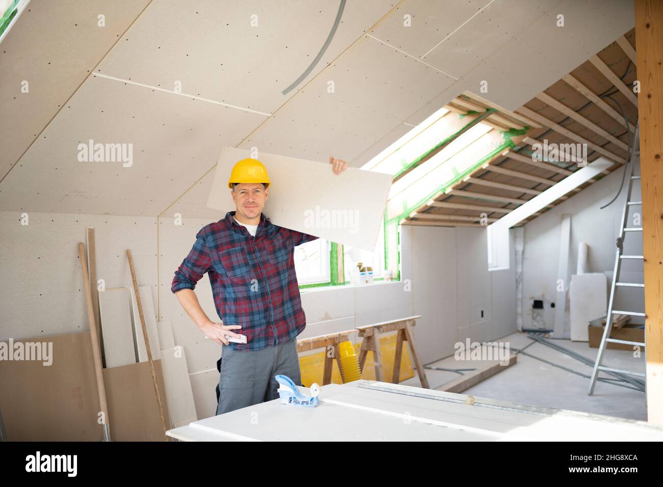 drywall worker with yellow safety helmet works on building site in a ...