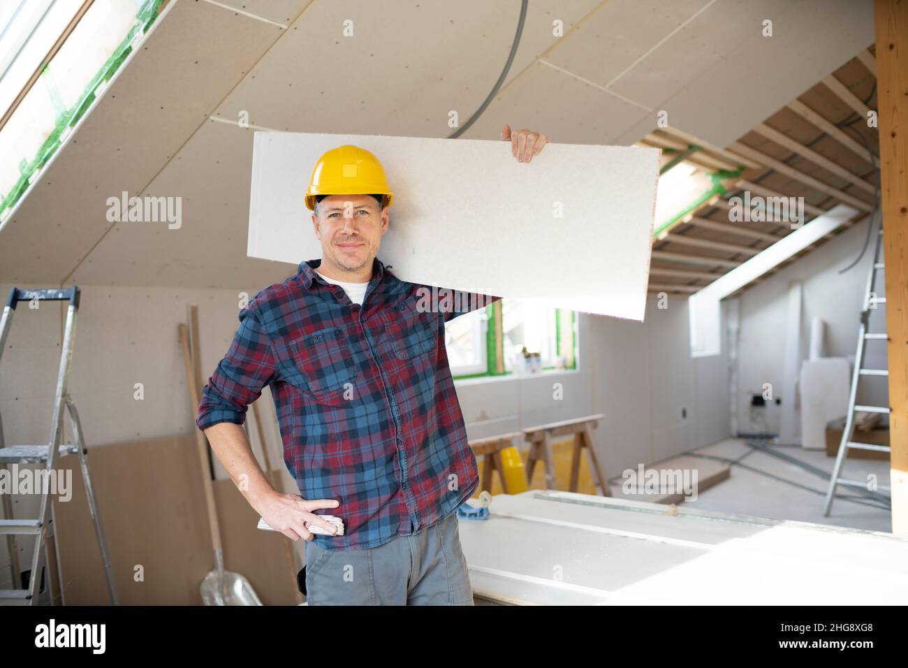 drywall worker with yellow safety helmet works on building site in a ...