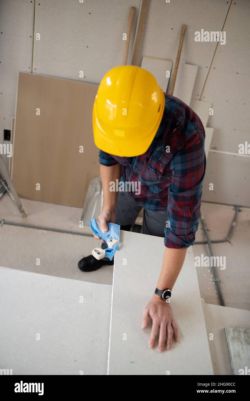 drywall worker with yellow safety helmet works on building site in a ...