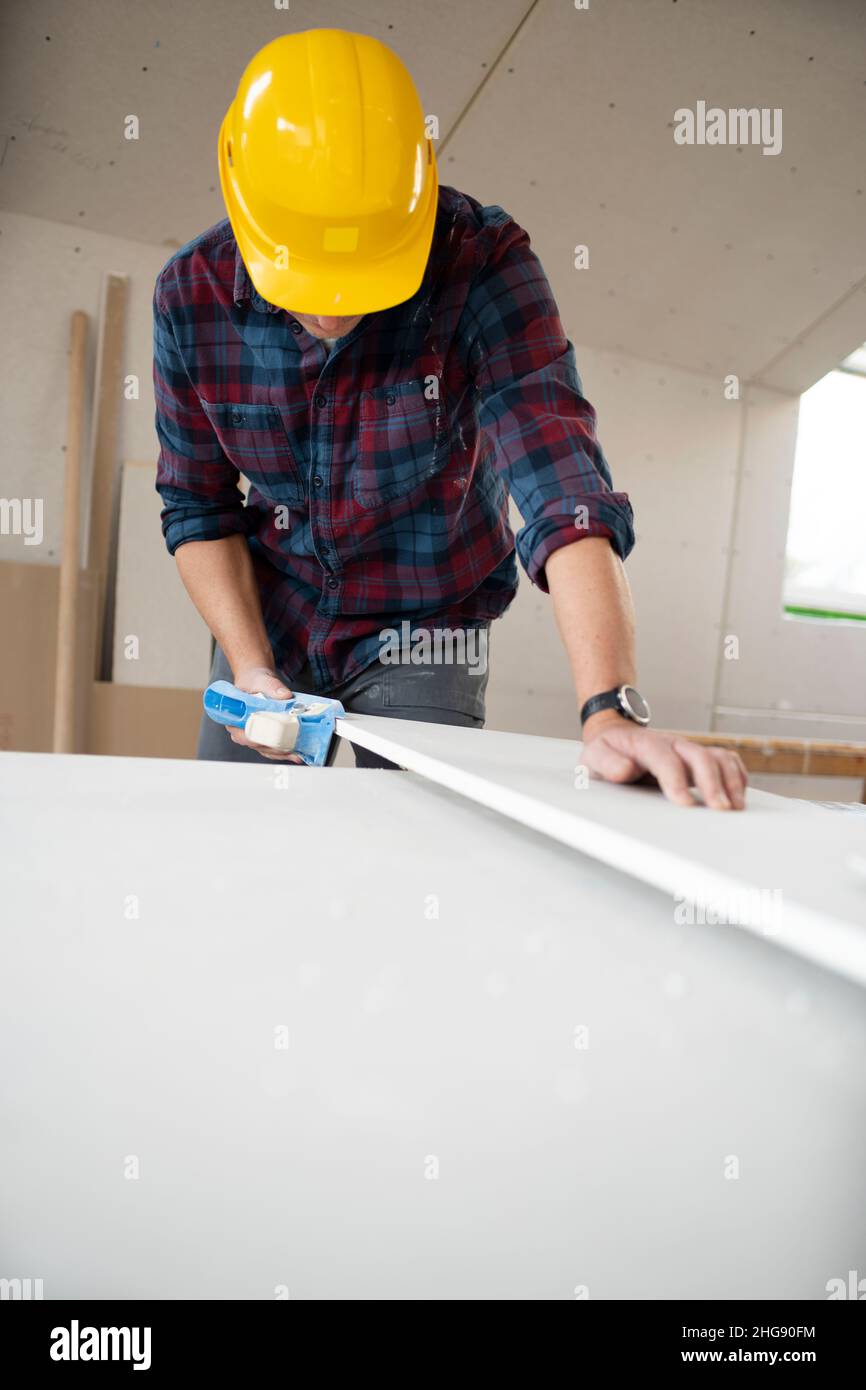 drywall worker with yellow safety helmet works on building site in a ...