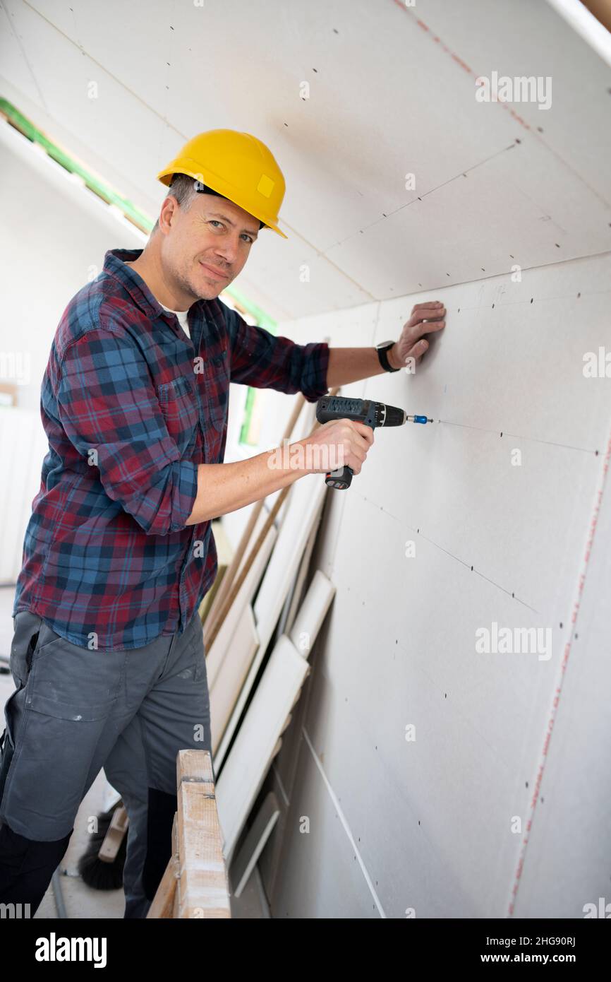 drywall worker with yellow safety helmet works on building site in a ...