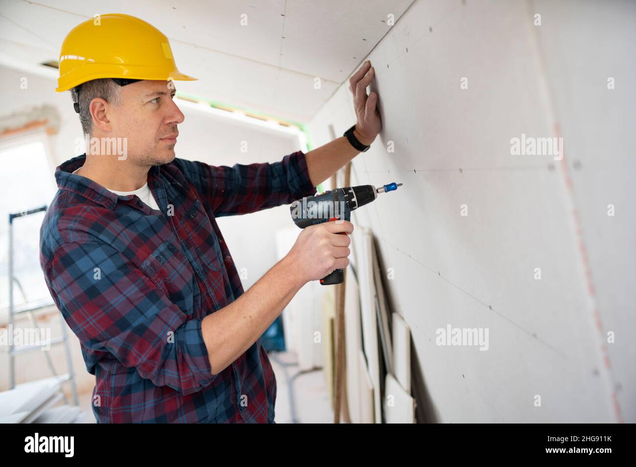 drywall worker with yellow safety helmet works on building site in a ...