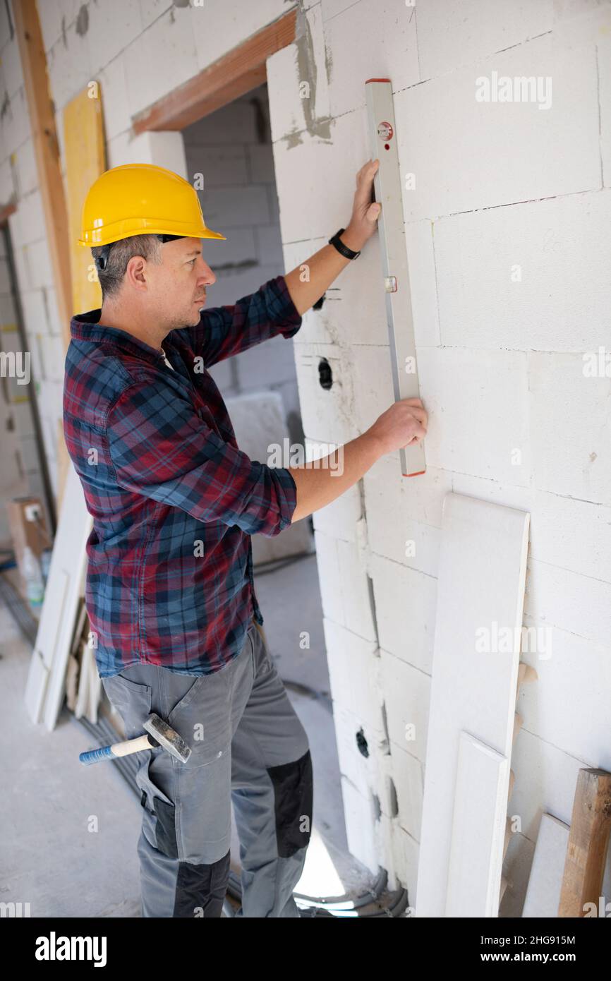 drywall worker with yellow safety helmet works on building site in a ...