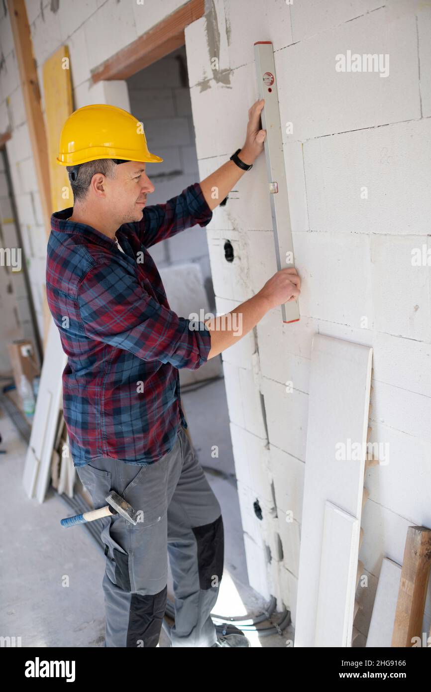 drywall worker with yellow safety helmet works on building site in a ...