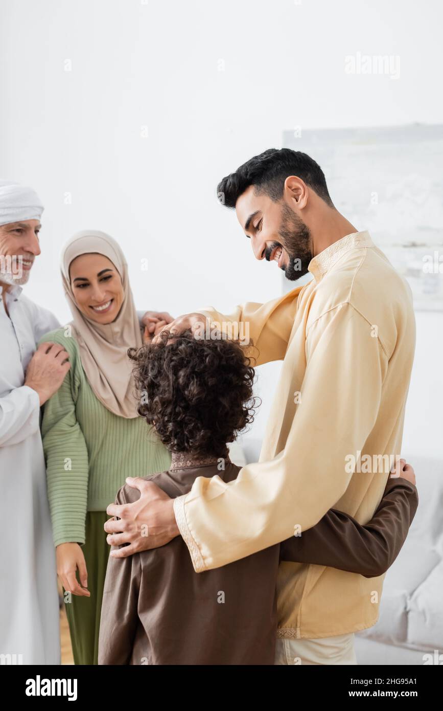 arabian father and son embracing near happy interracial muslim family ...